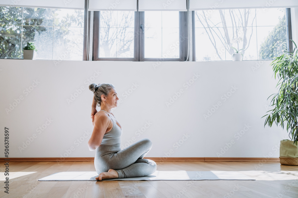 Side view of the senior grey haired woman stretching at home with the ...