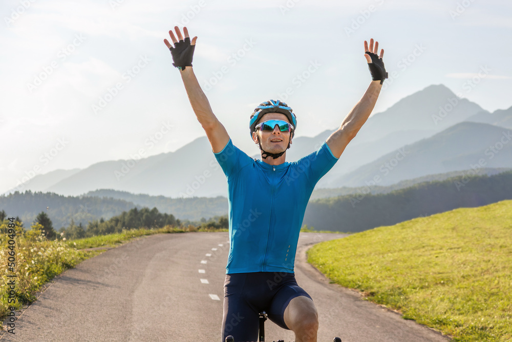 Male athlete professional racing cyclist riding a bike with arms raised ...