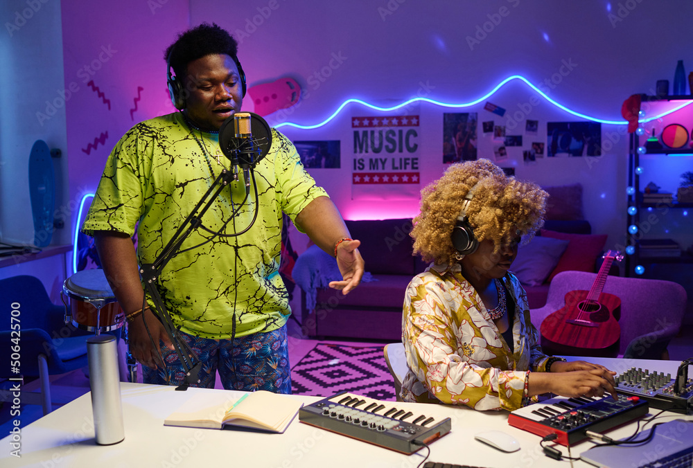 Stylish gen Z African American man rapping or singing into microphone ...