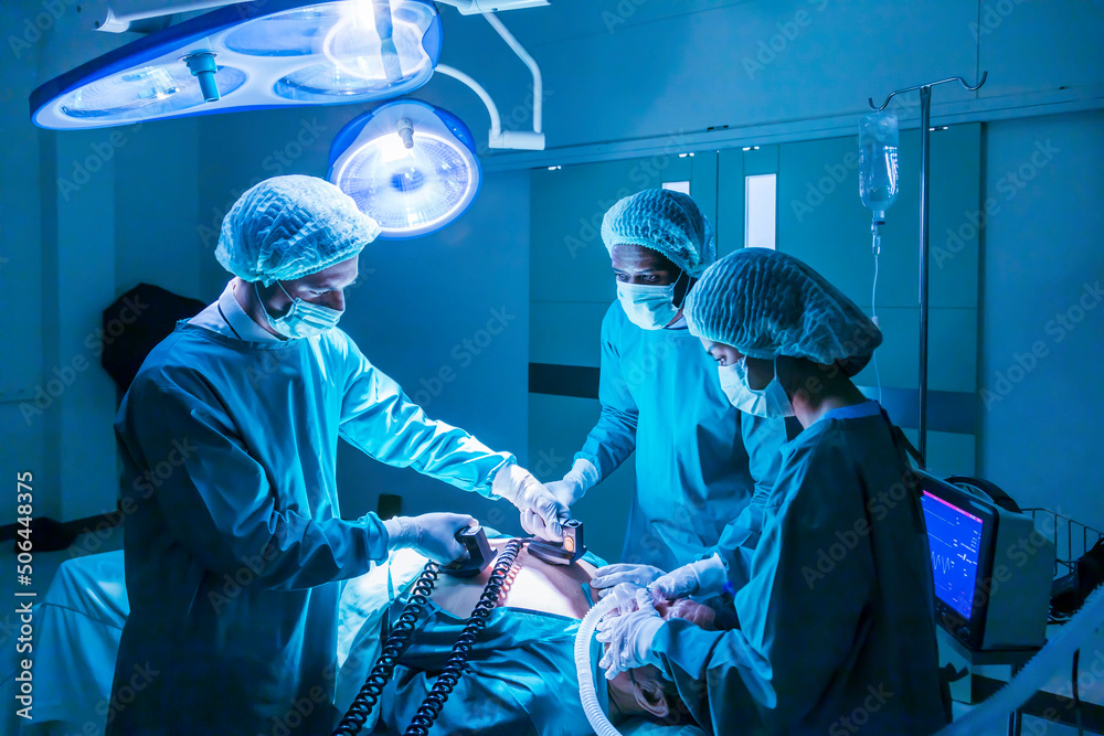 Team of surgeon doctor using defibrillator to give electrical shock to ...