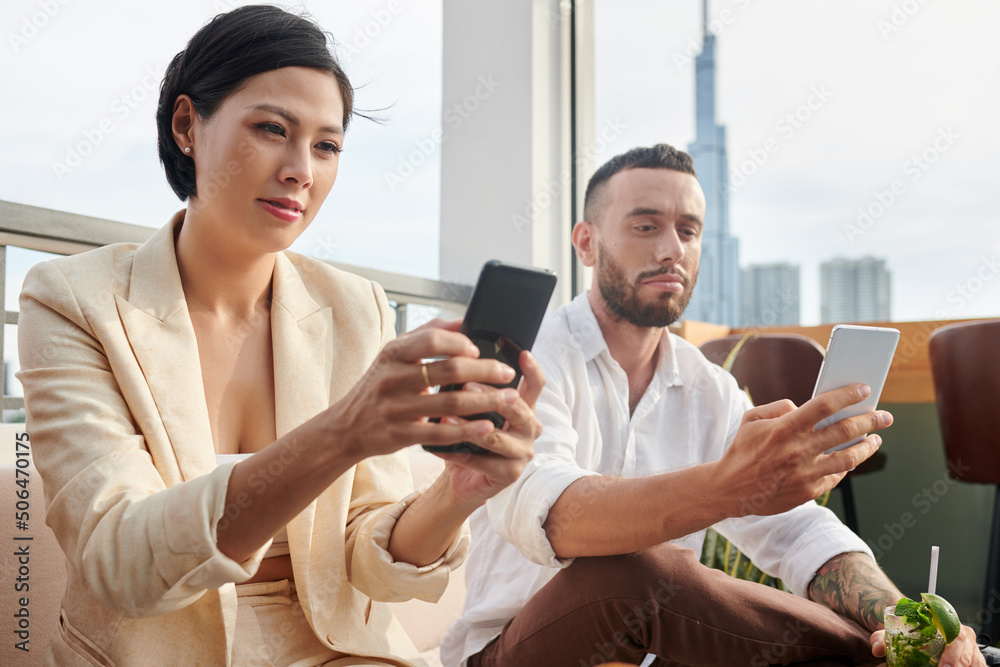 Young people checking smartphones when hanging out together in rooftop ...