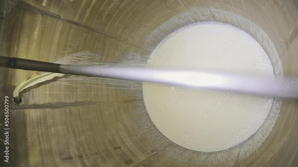 Ice cream preparation. Stirring milk in a factory. Milk rotates in a ...