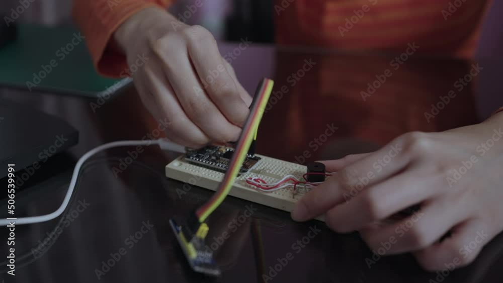 Close-up, hand of woman plugging a pin on an electronic circuit board ...
