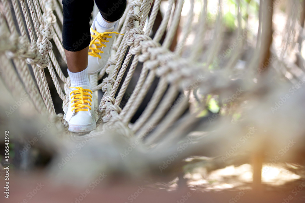 Little child girl play walking on rope bridge on adventure park, close ...