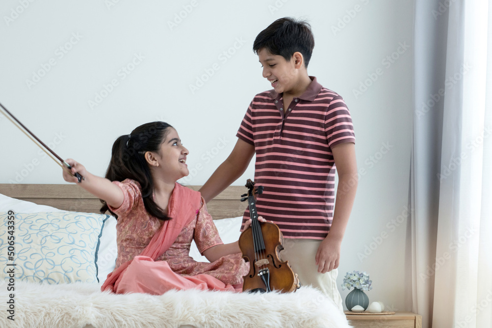 Indian brother and sister, girl practicing her violin in bedroom, older ... Indian brother and sister, girl practicing her violin in bedroom, older ...