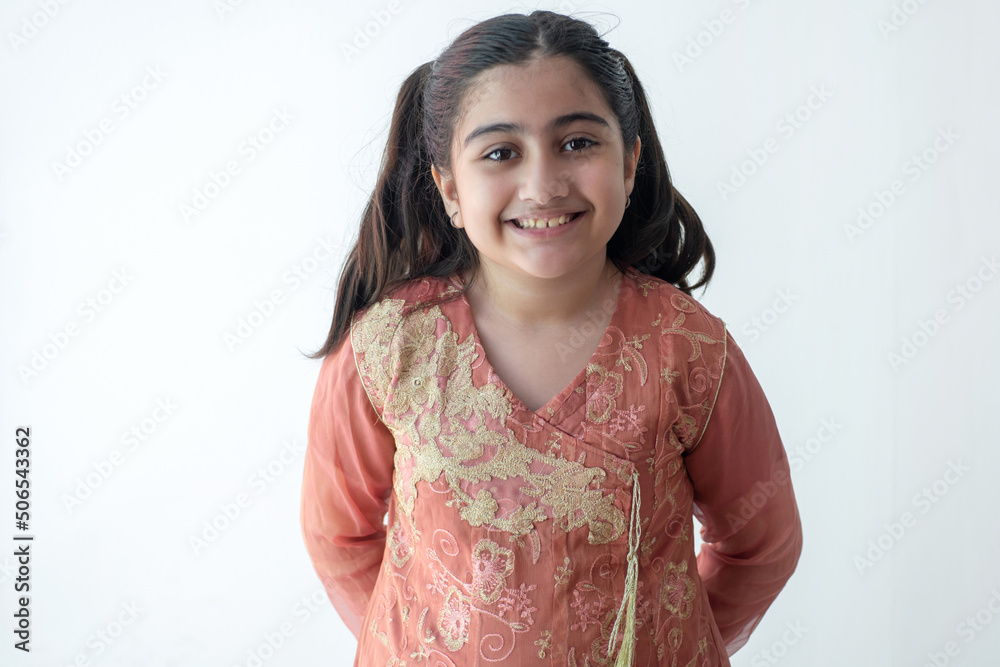Portrait of Pakistani little girl smiling at camera against white ...