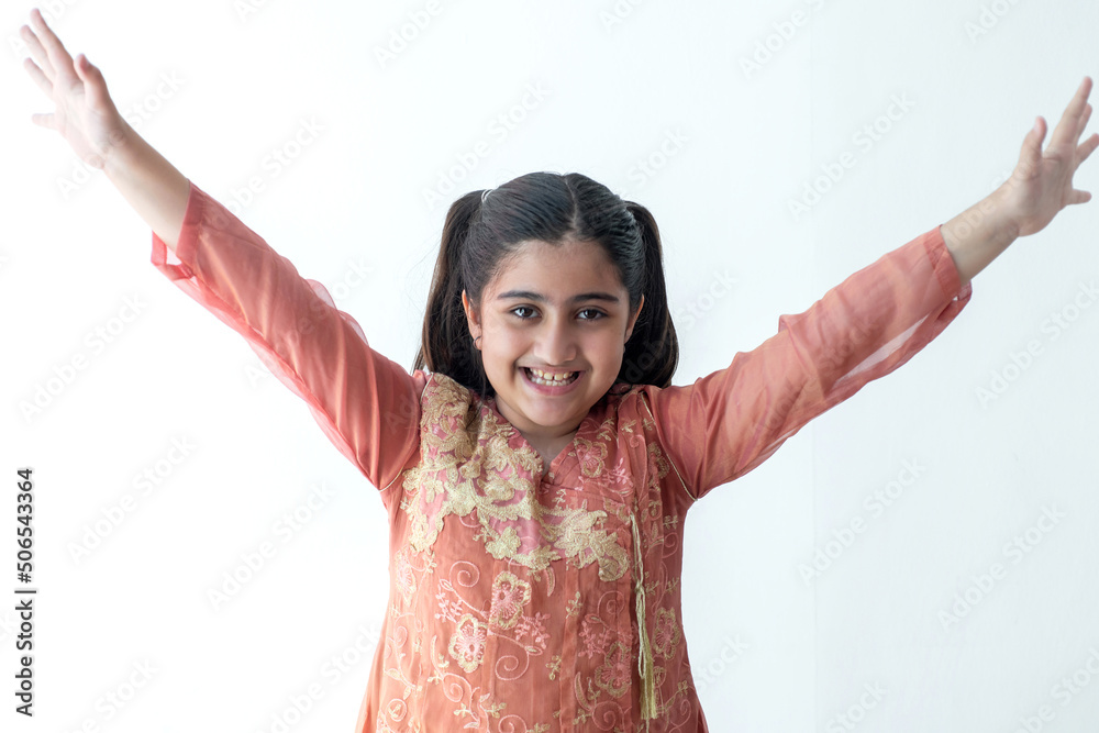 Portrait of Pakistani little Girl standing and raising hand up against ...