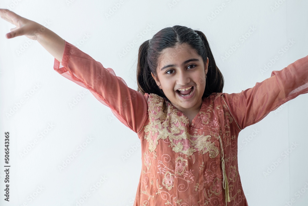 Portrait of Pakistani little girl standing and raising hand up against ...