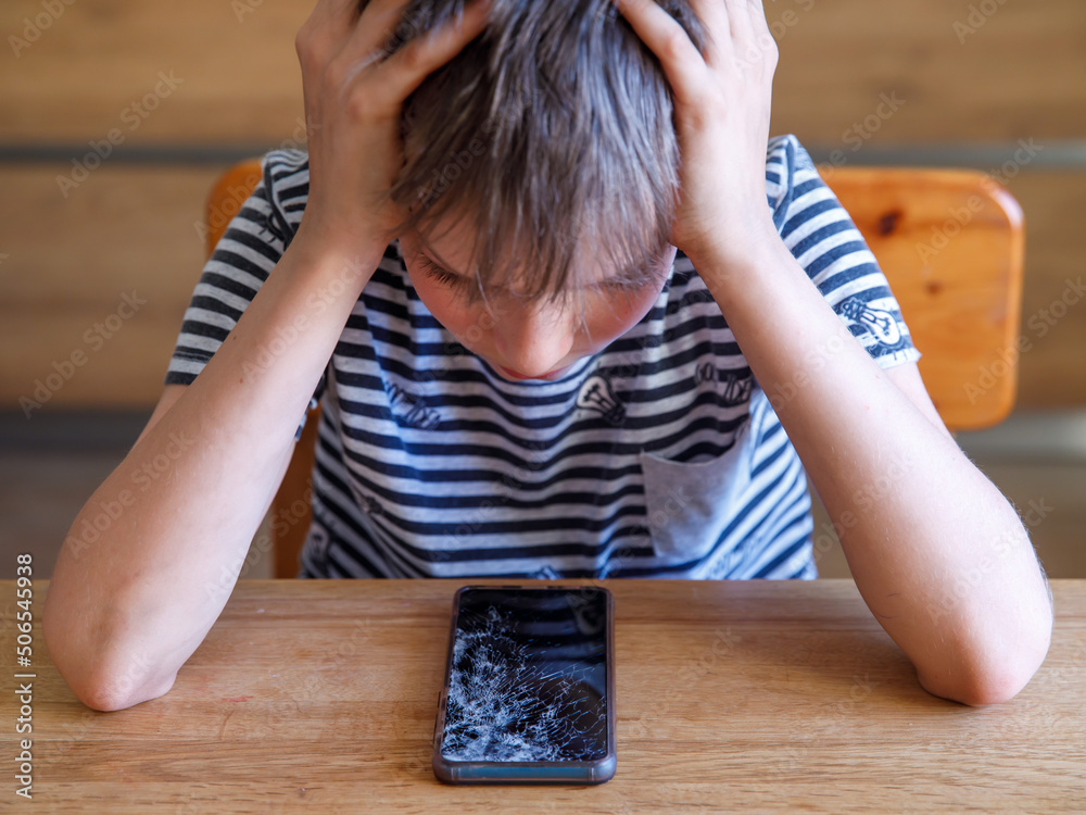 Portrait of scared kid girl with broken mobile phone on table. Sad ...