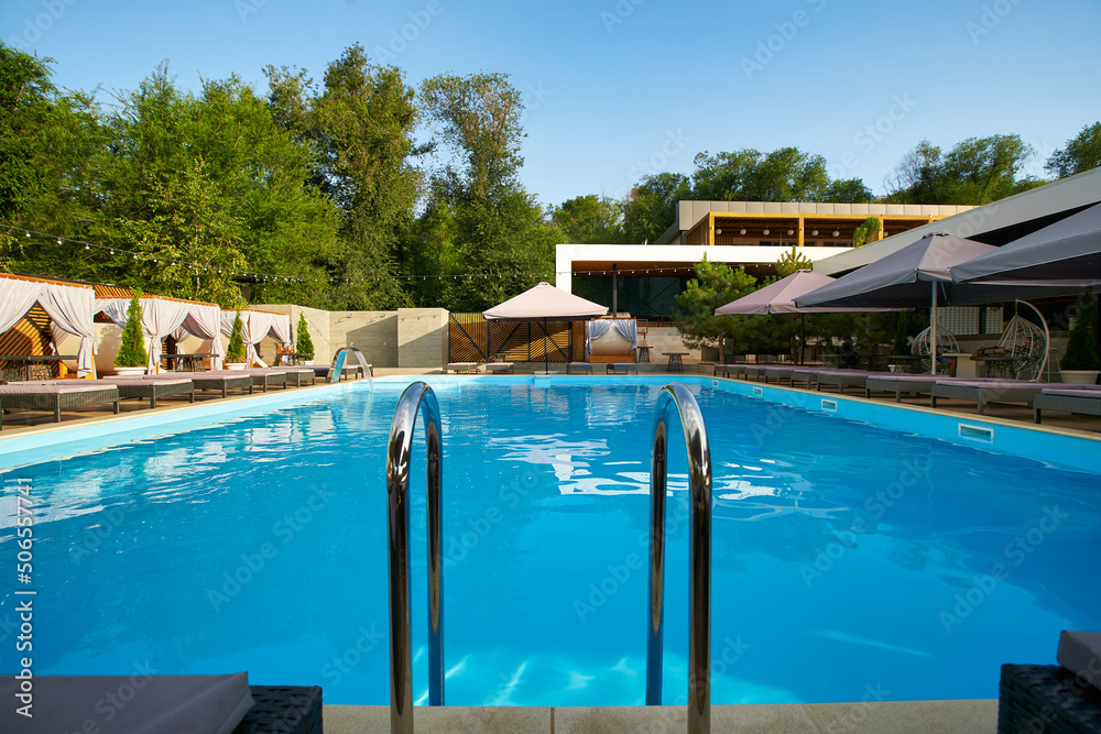 Swimming pool area with ladder, gazebos, deck chairs and sun umbrellas ...