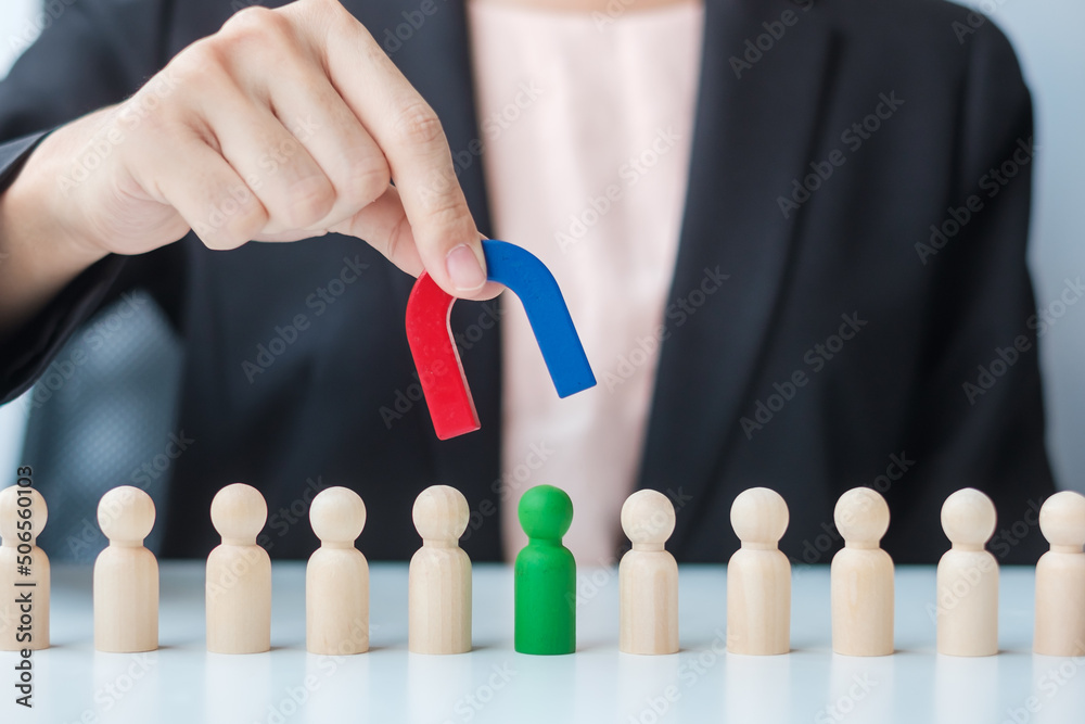 Business woman hand holding magnet and pulling man wooden figure from ...