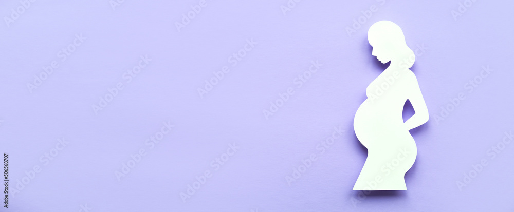 Paper silhouette of a pregnant woman casts a shadow on a lavender ...