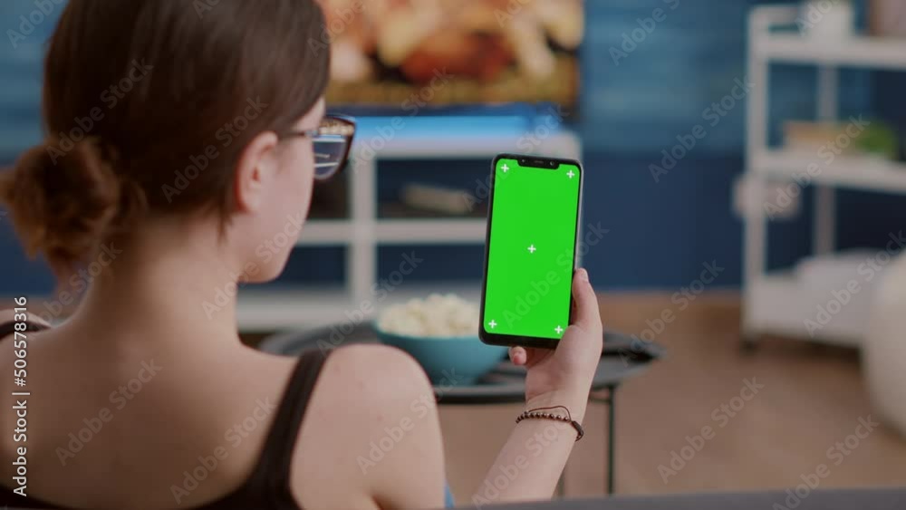 Closeup of young woman holding vertical smartphone with green screen ...