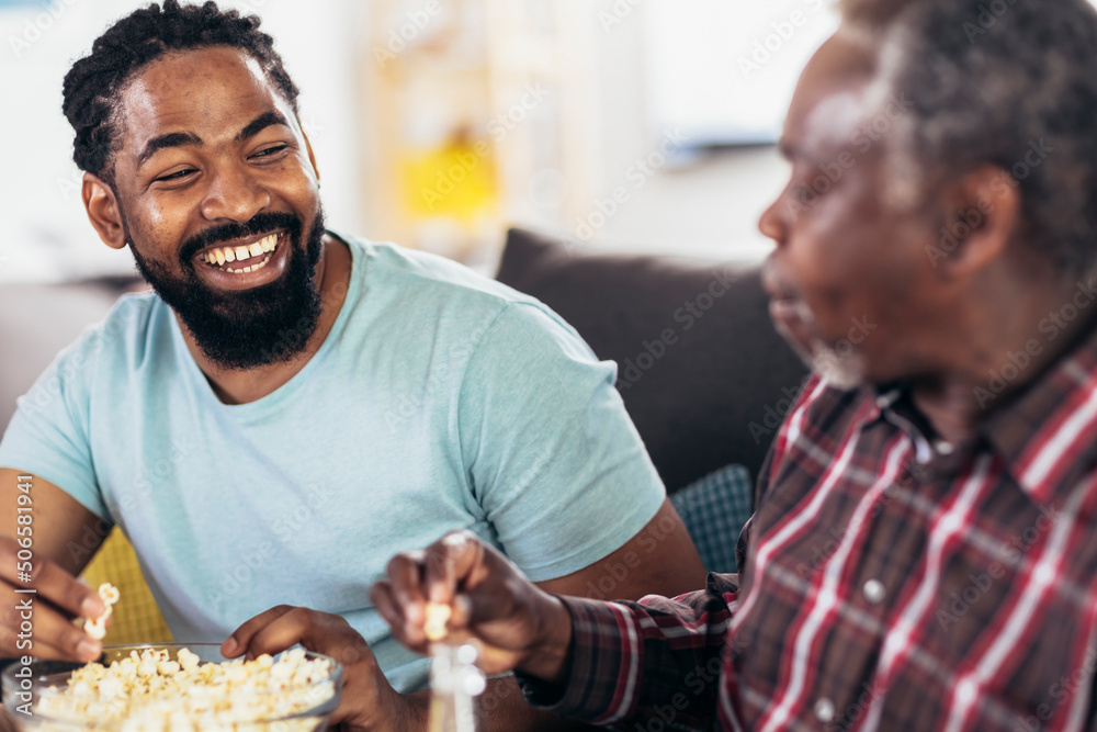 Excited old father and son watching tv, eating popcorn snack, having ...