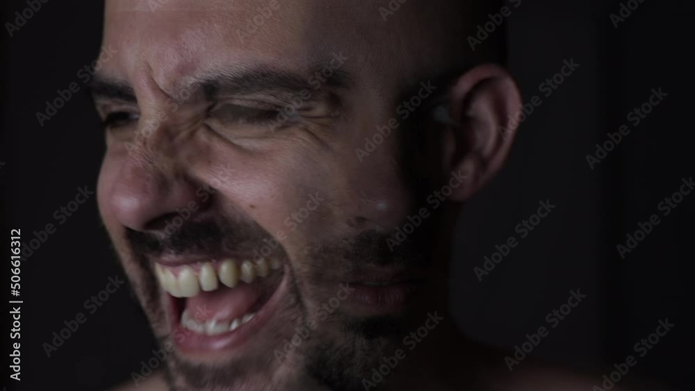 Disturbed man with schizophrenia symptoms. Low key light face with ...