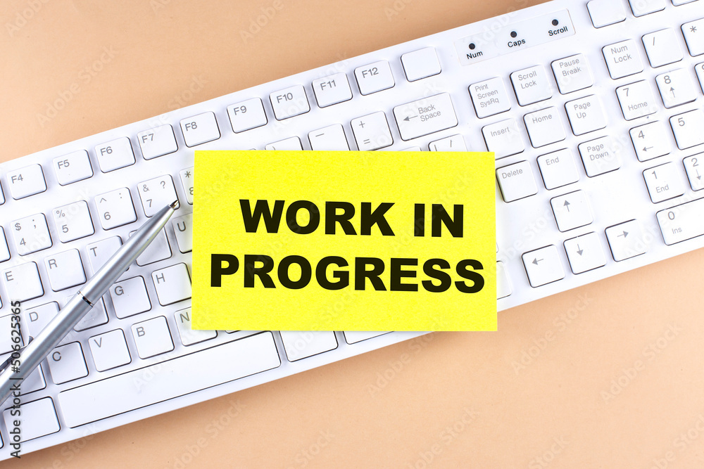 Text WORK IN PROGRESS text on a sticky on keyboard, business concept ...
