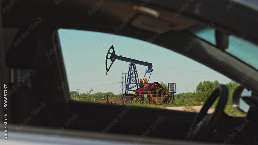 View through the open car window of working oil pump rig. Oil and gas ...