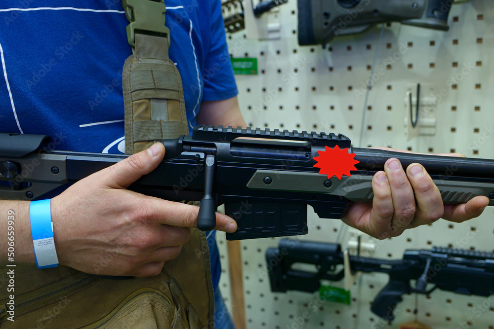Man hands holding a new model of a rifle in a gun shop, rifles on a ...