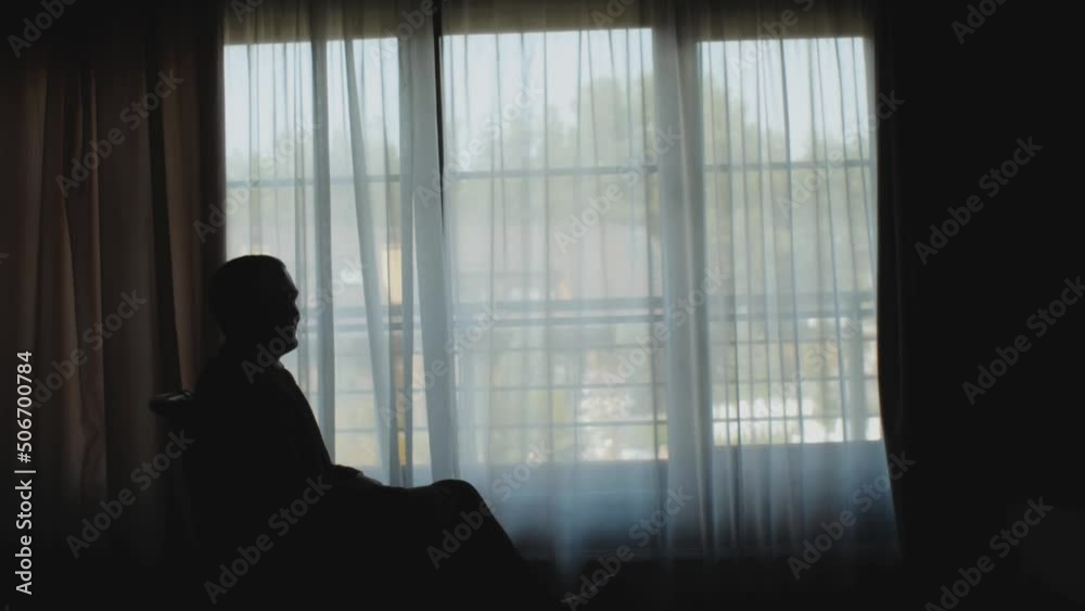 Silhouette of man walking from a dark room to the window. Guy in ...
