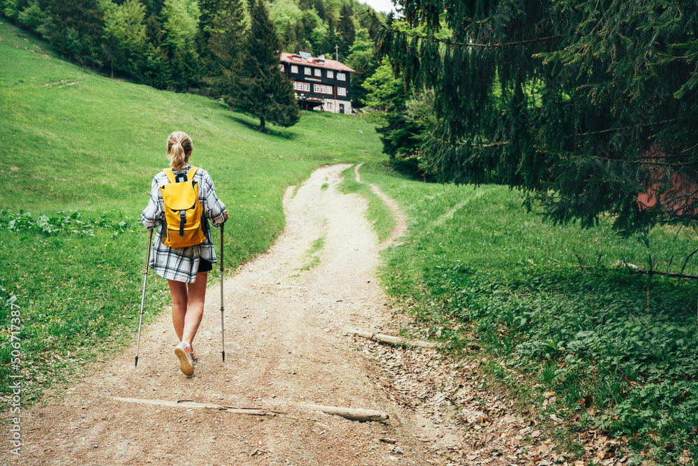 Lonely female with yellow backpack walking by mountain path with ...