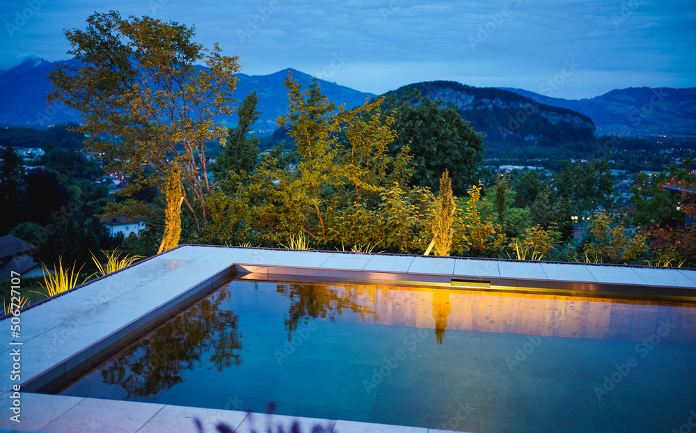 Evening view of a illuminated swimming pool with wooden walls in a ...