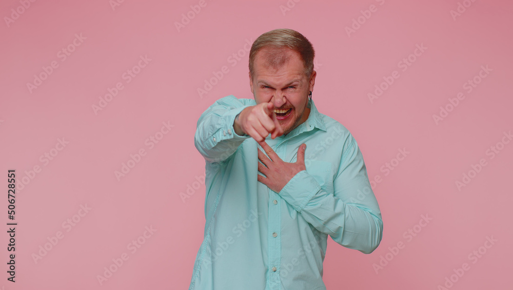 Amused man in casual blue shirt pointing finger to camera, laughing out ...