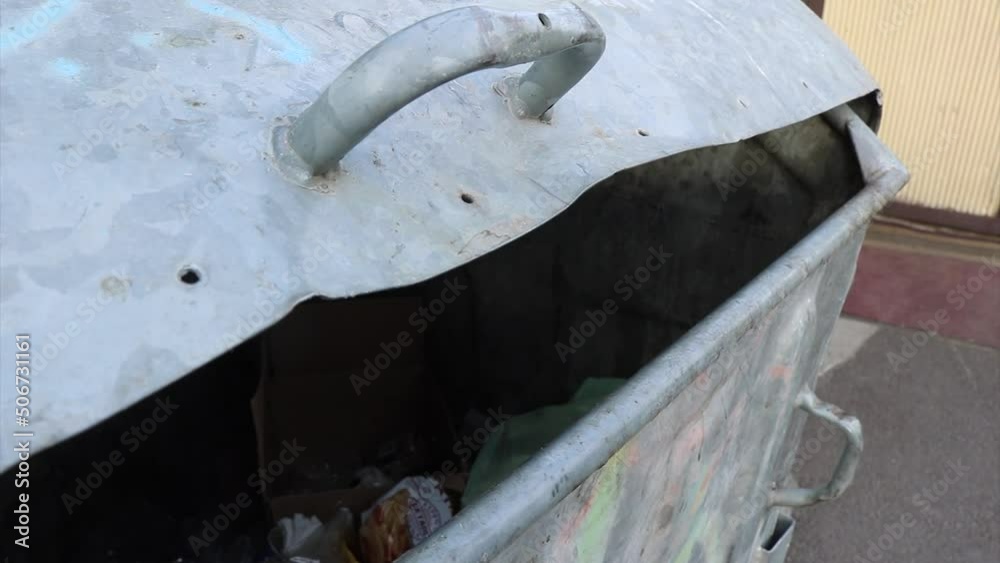 throwing crumpled paper garbage into an old garbage container - young ...