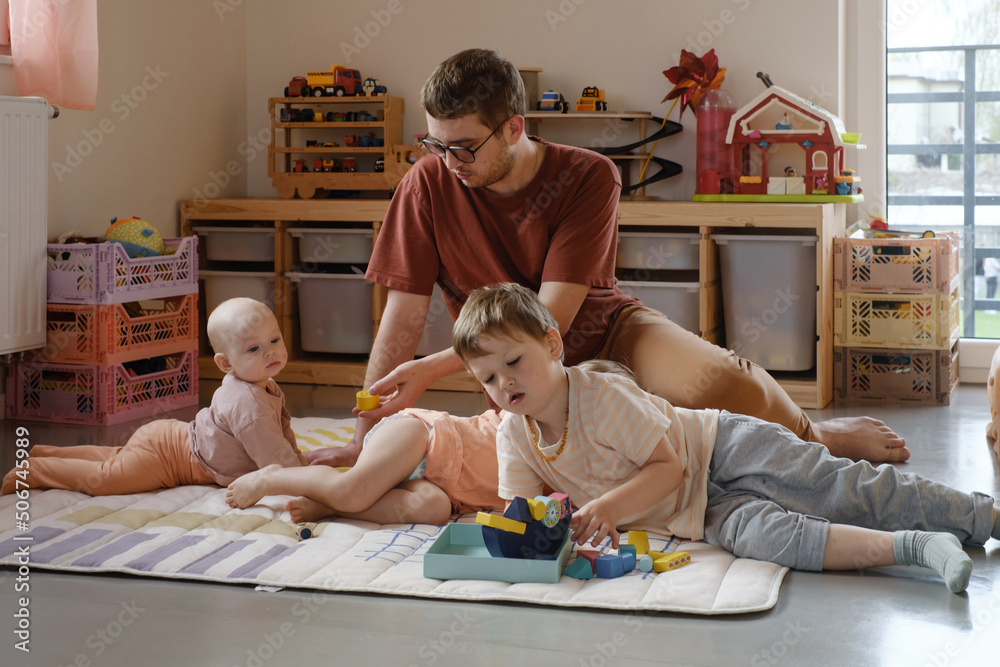 Big family in sunny play room. Parents playing with kids and toys ...