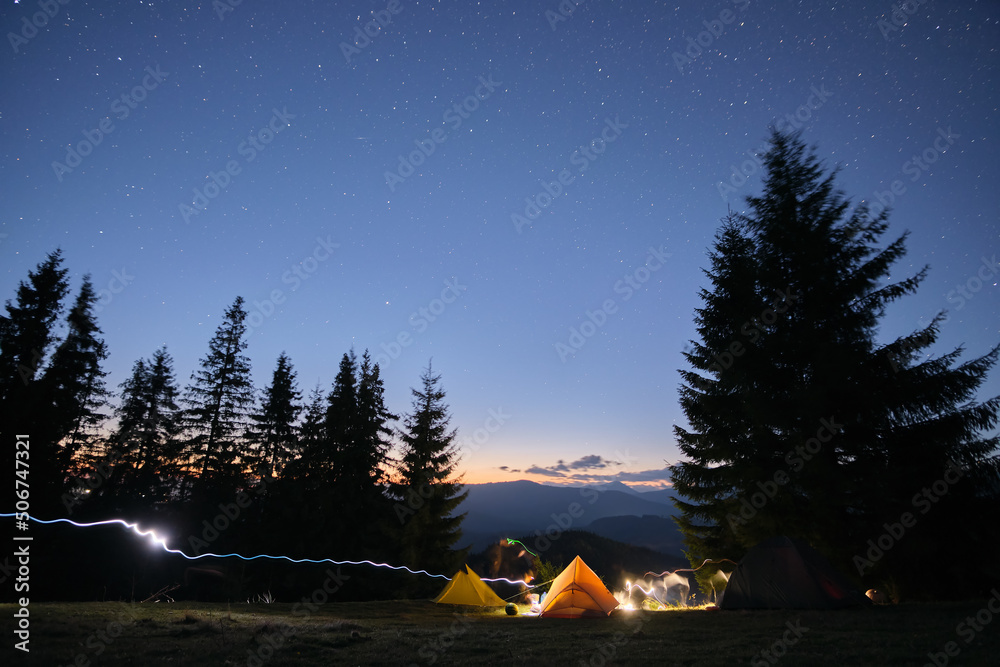 Bright illuminated tourist tents glowing on camping site in dark ...