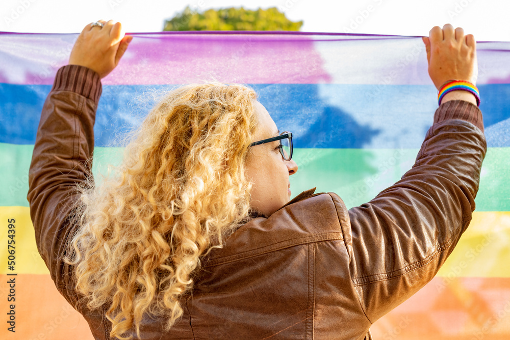 Back view or a lesbian activist holding a LGBT rainbow flag. Concept of ...
