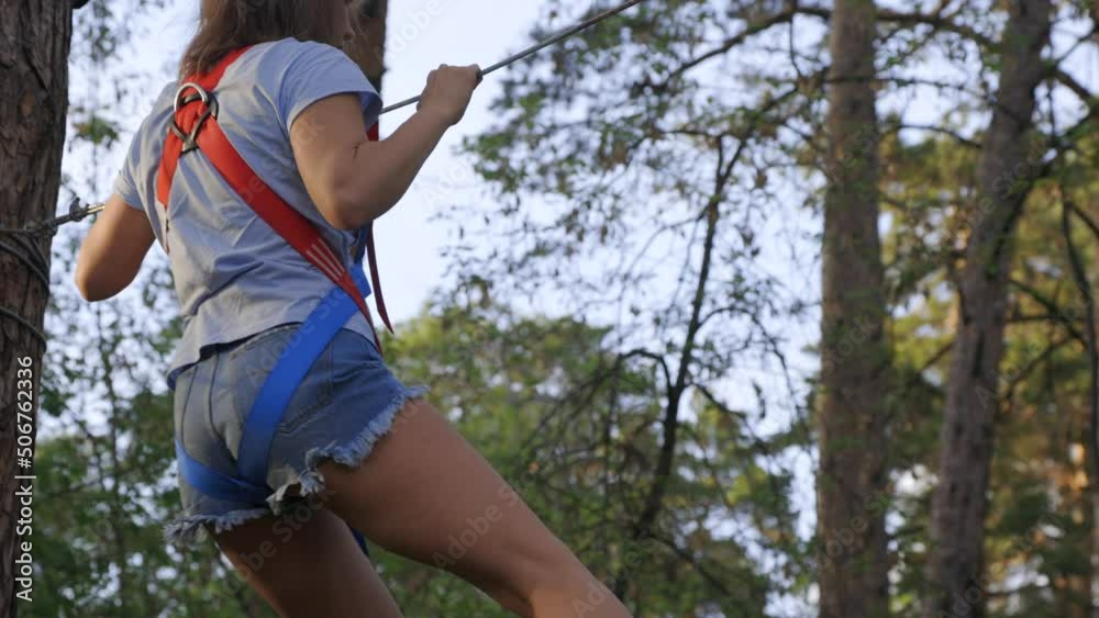 Young girl in denim shorts deftly walks on a rope holding on to the ...