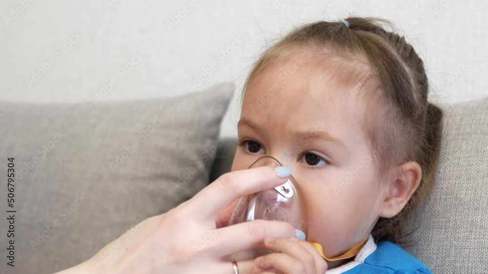 Mother makes inhalation with nebulizer to her daughter. Hand of woman ...
