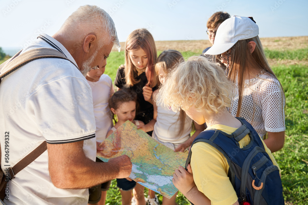 Close up of old man wearing white T-shirt and rucksack, showing map to ...