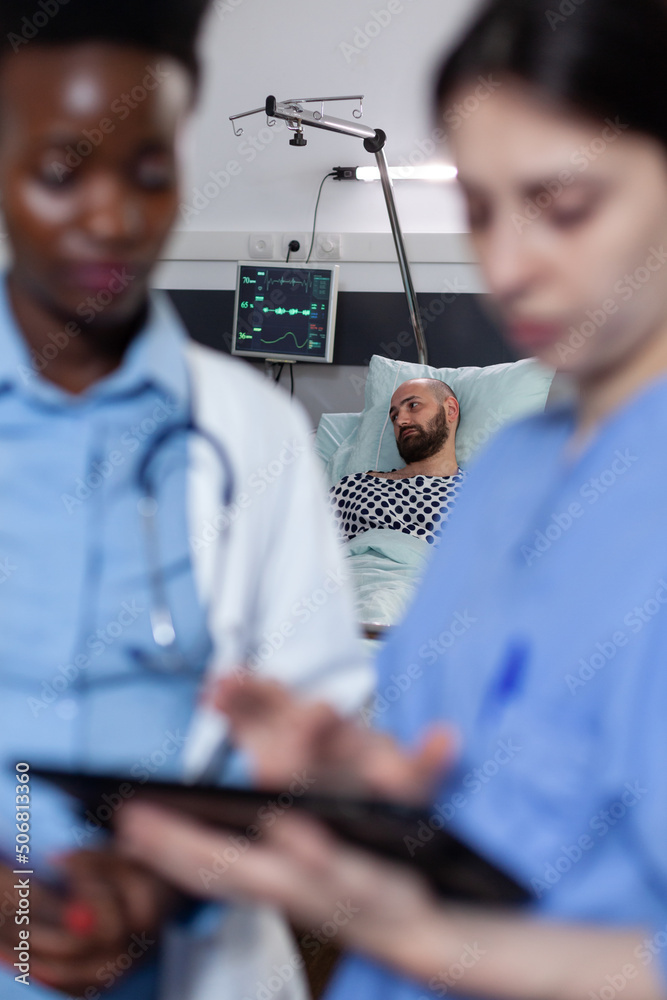 Doctor and nurse reading digital test results on tablet for man with ...