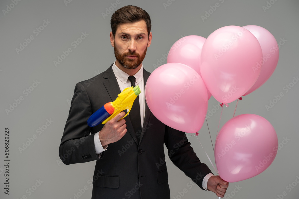 Serious businessman wearing formal suit holding toy gun and a lot of ...