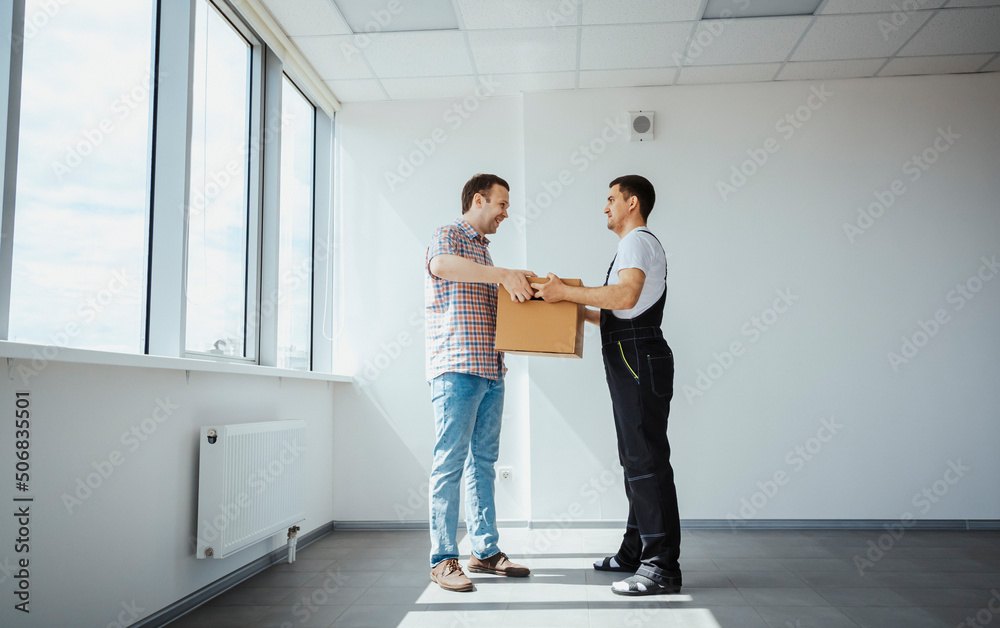 Caucasian man receiving a package at home from a delivery guy. A happy ...