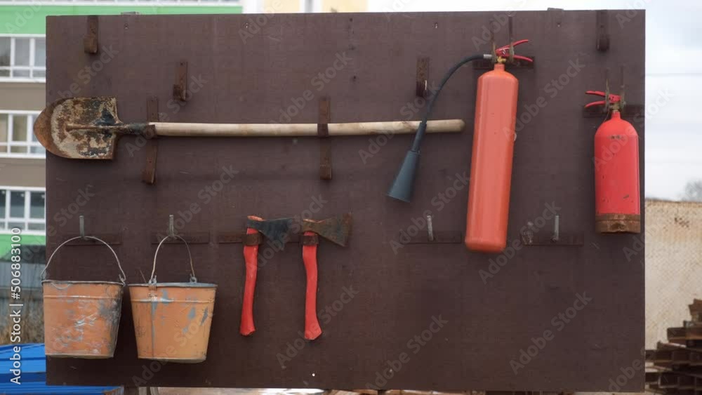Board with a shovel, fire extinguishers, buckets and axes on the ...