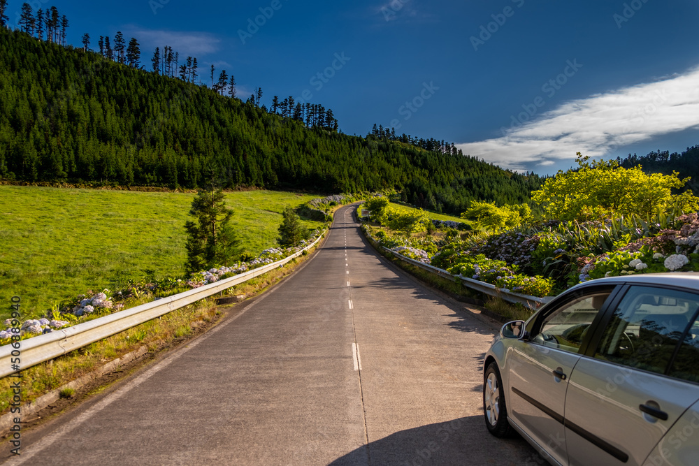 Traditional road with a car side and the green landscape and blue ...