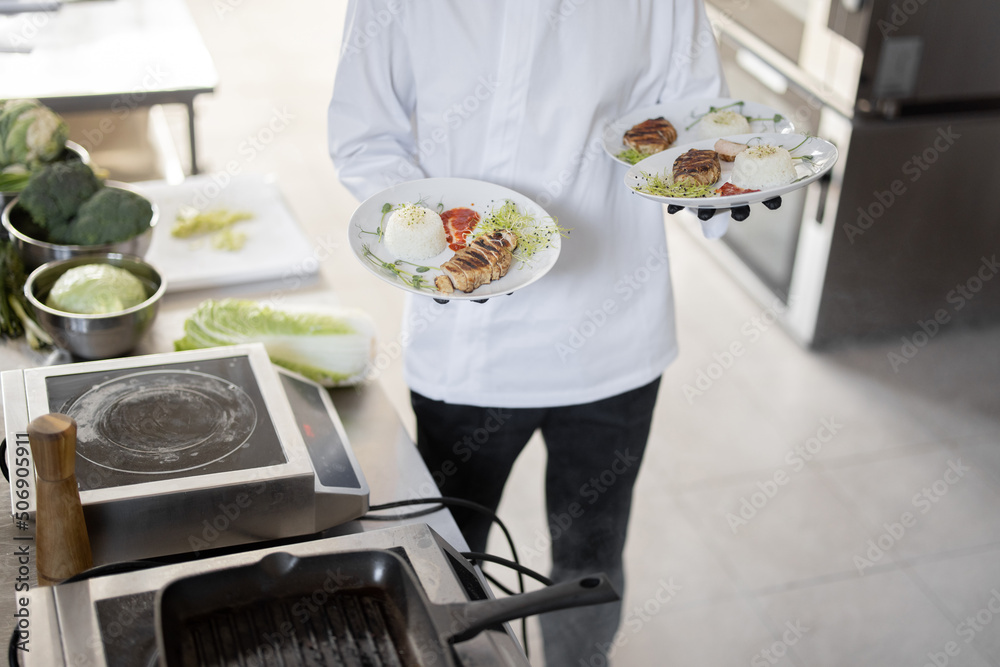 Chef holding three plates with ready meals, carrying them on hands ...