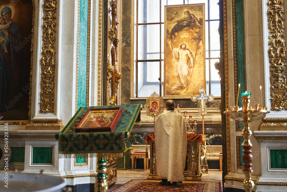 Orthodox Church. a priest behind an altar adorned with gold and icons ...