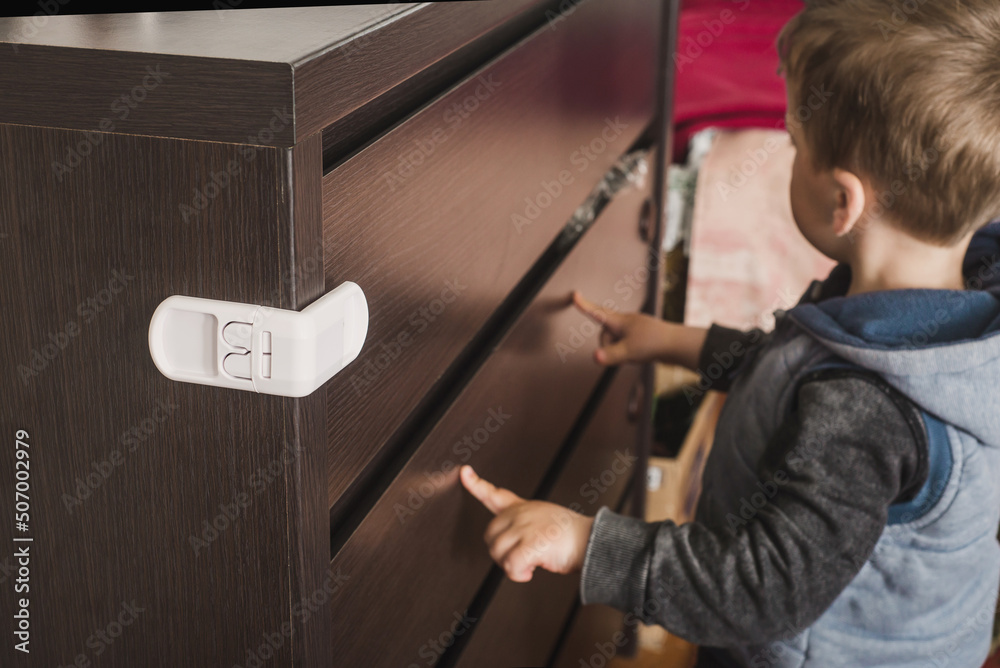 A small child opens a chest of drawers with clothes and goes through ...