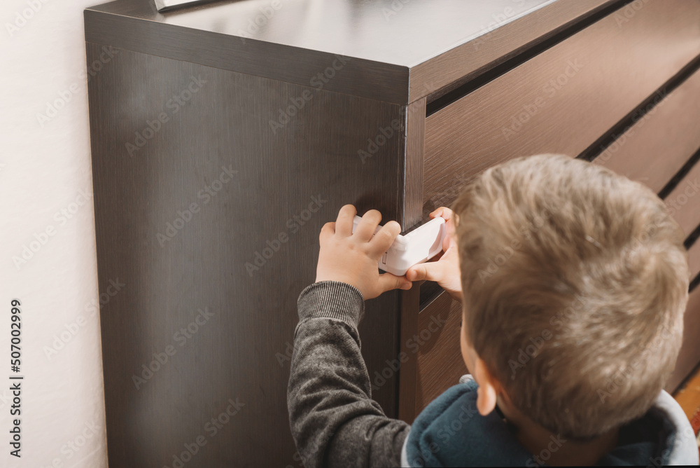 A small child opens a chest of drawers with clothes and goes through ...