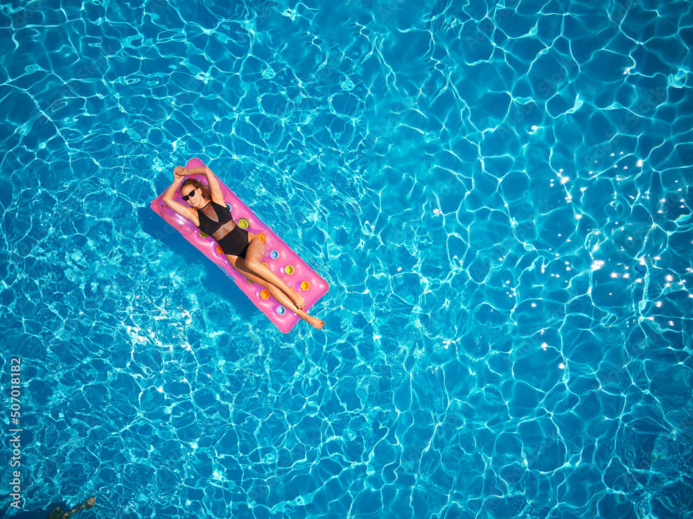 Fit pretty girl in bikini chilling on inflatable pink mattress in ...