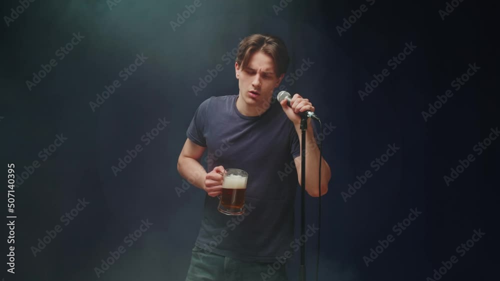 Drunk man singing on stage and drinking beer. Young guy in karaoke ...