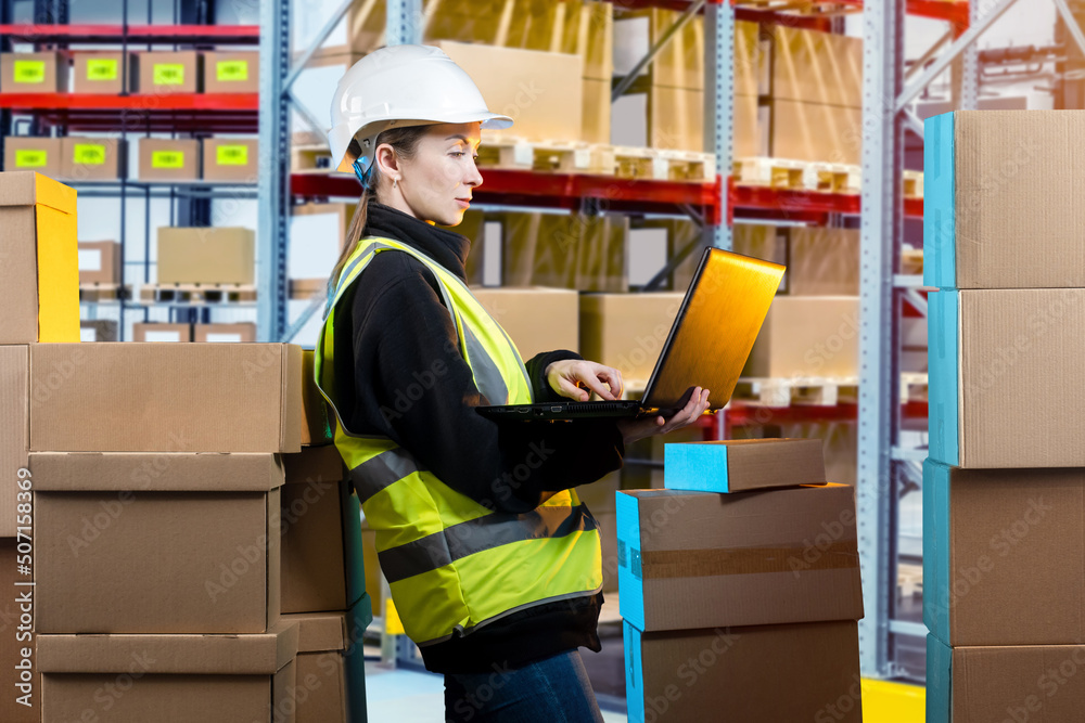 Logistics warehouse worker. Woman logistician stands with laptop in her ...