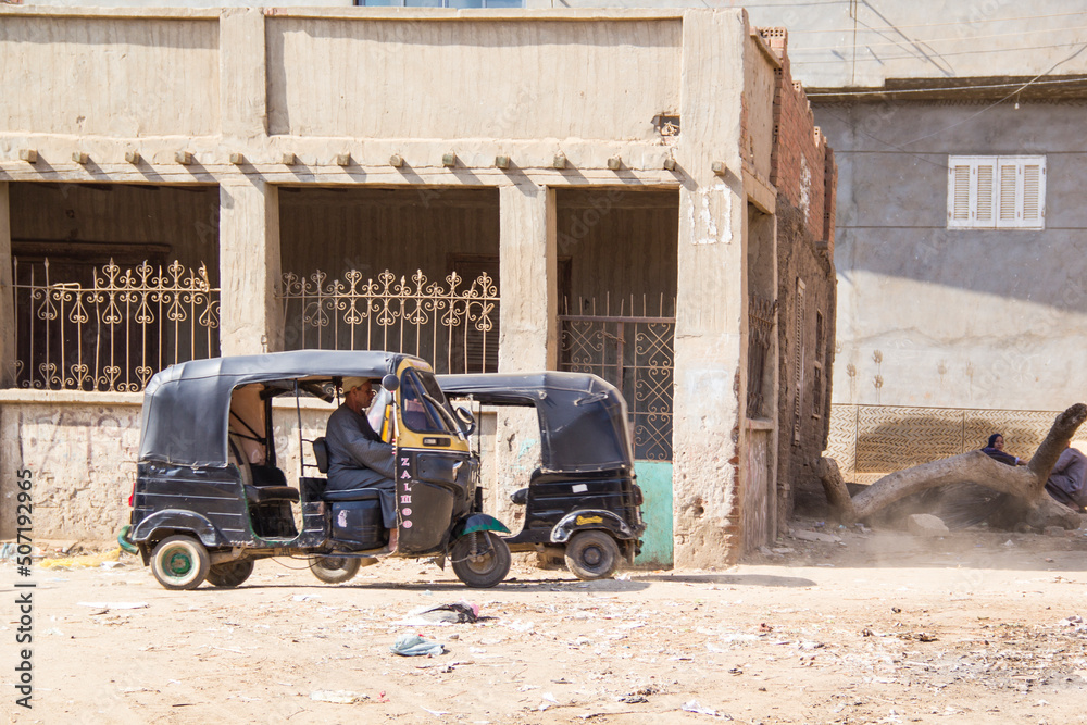 CAIRO, EGYPT - DECEMBER 29, 2021: Two men on a Tuk Tuk in a traditional ...
