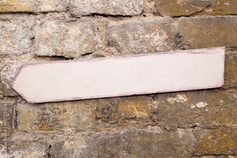 Arrow wooden sign hanging on a rustic brick wall. Emty space, add text ...