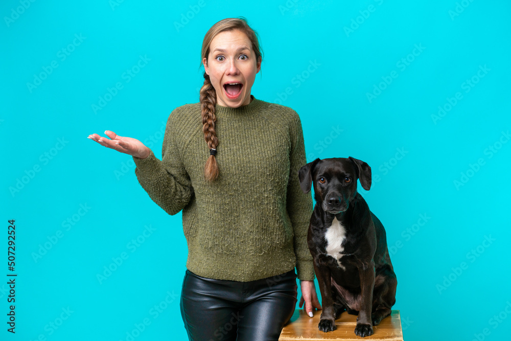 Young caucasian woman with her dog isolated on blue background with ...