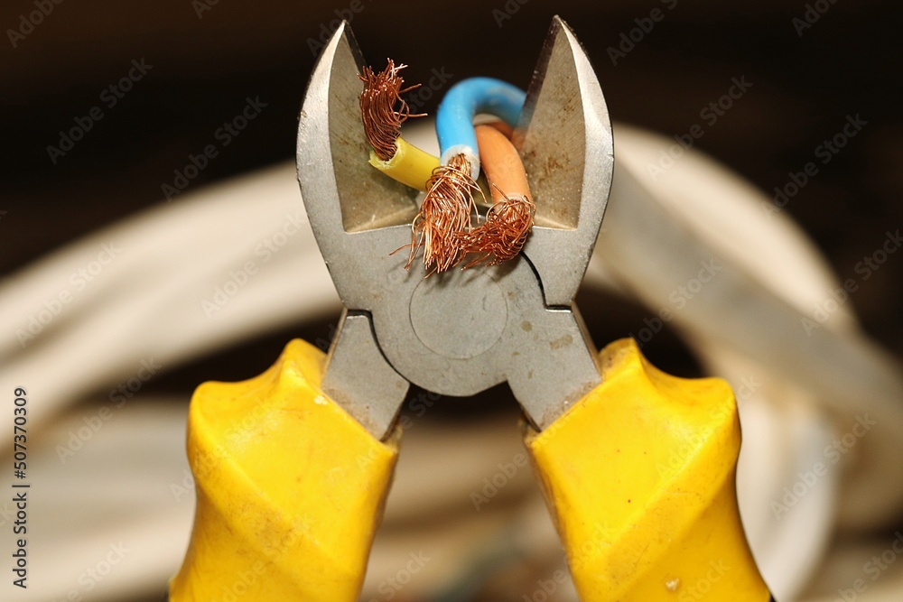 Electrical wires in the process of being cut with a side cutter. The ...