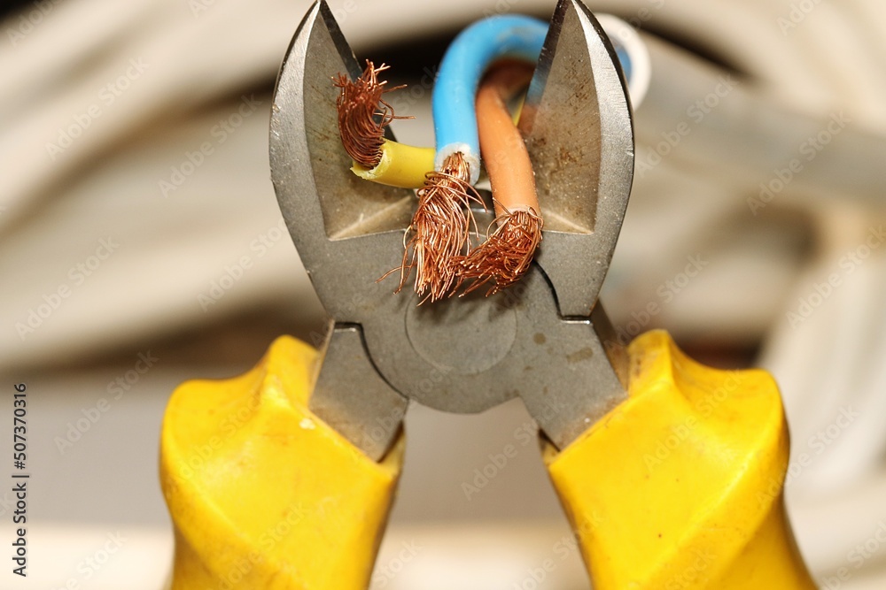 Electrical wires in the process of being cut with a side cutter. The ...